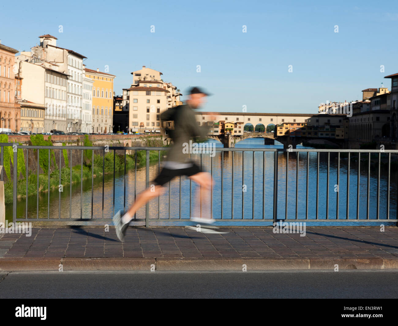 Italy, Florence, Man jogging past Ponte Vecchio over River Arno Stock ...