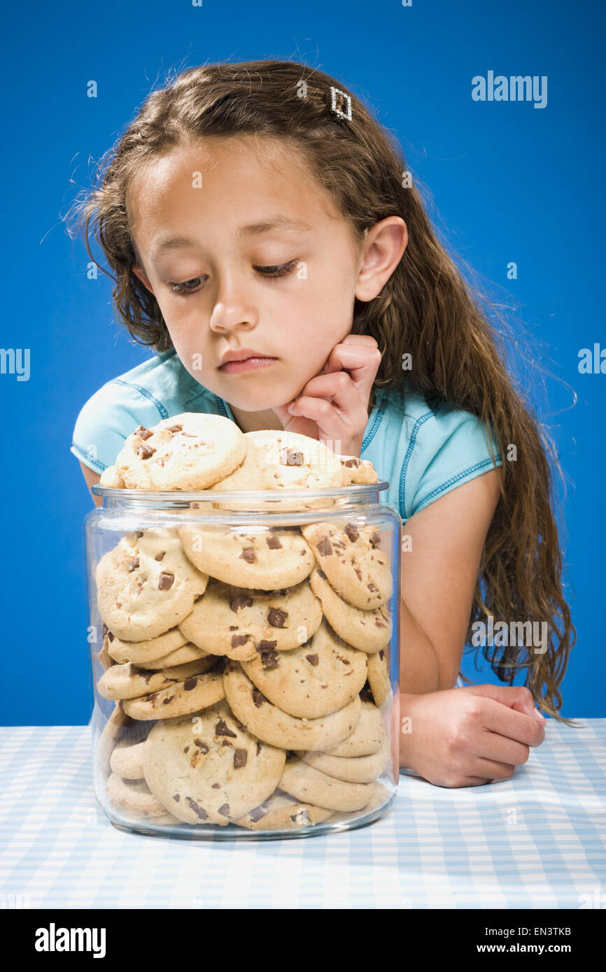 Girl looking at chocolate chip cookies in cookie jar Stock Photo - Alamy