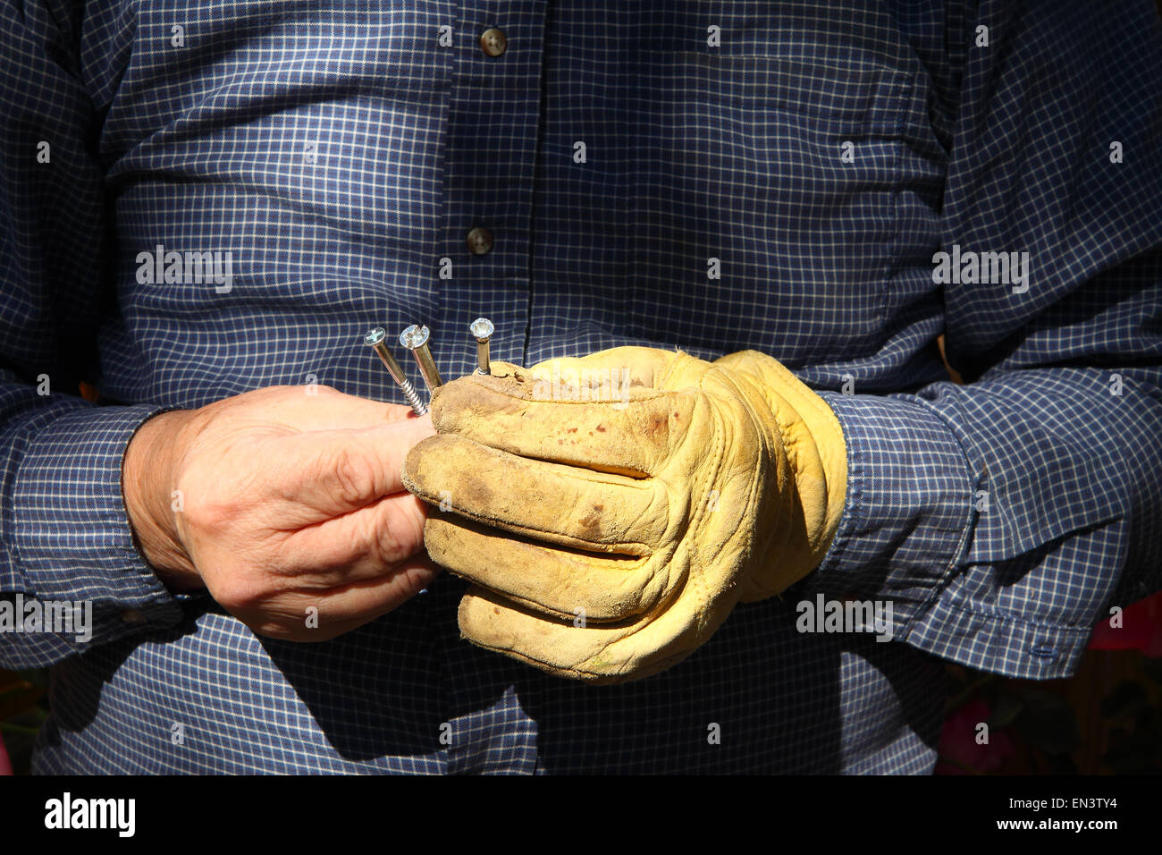 A man working outdoors holds three screws in his hands Stock Photo - Alamy