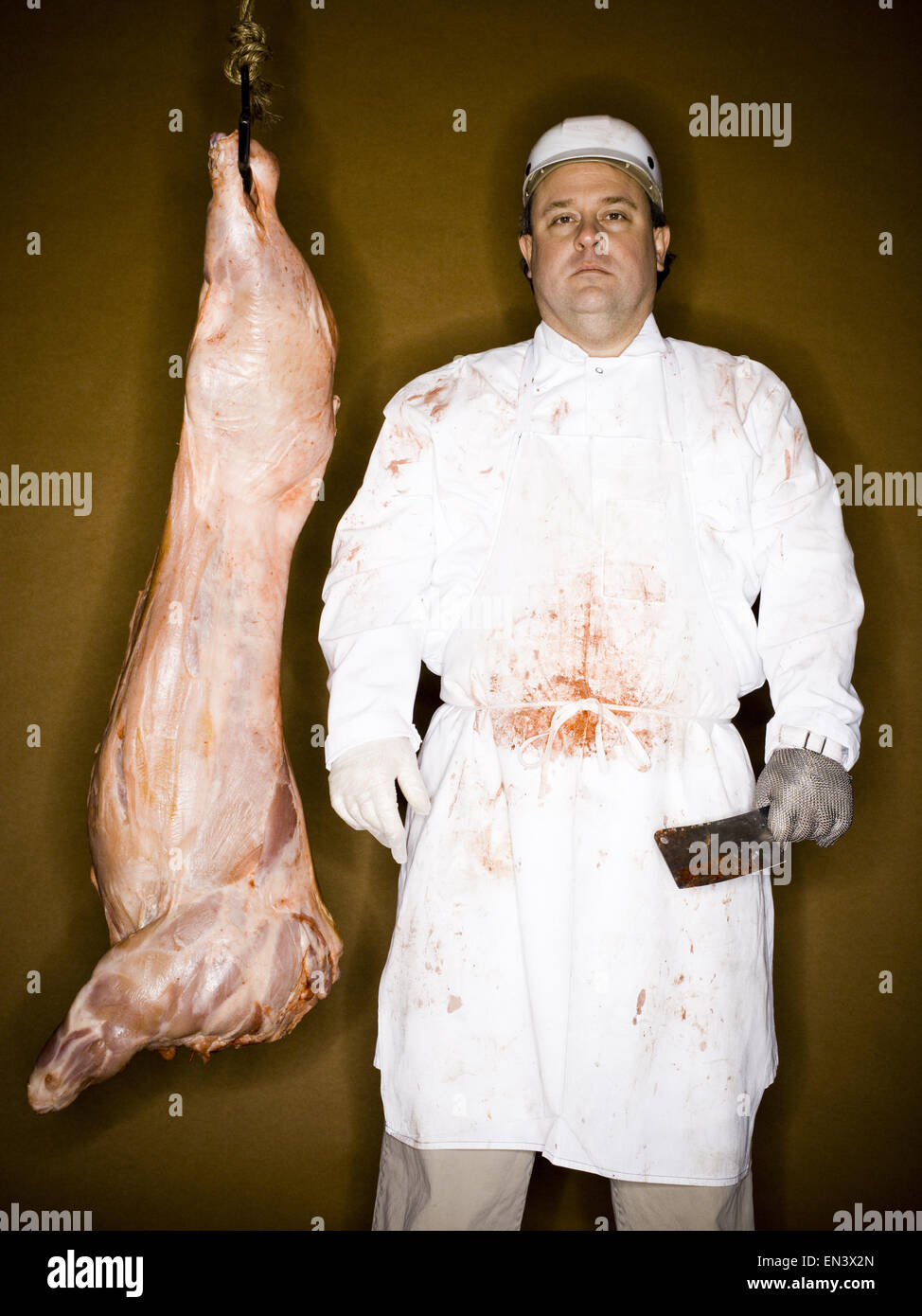 Butcher with hanging carcass and knife smiling Stock Photo - Alamy