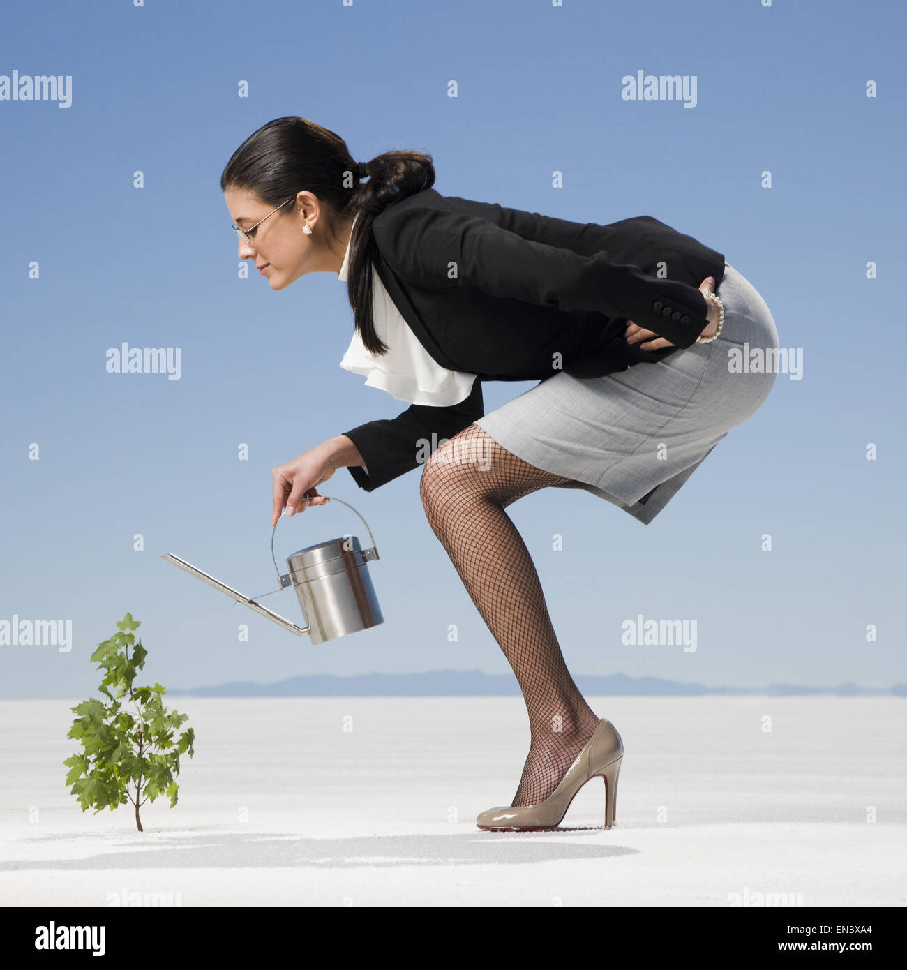 businesswoman watering a sapling in the desert Stock Photo - Alamy