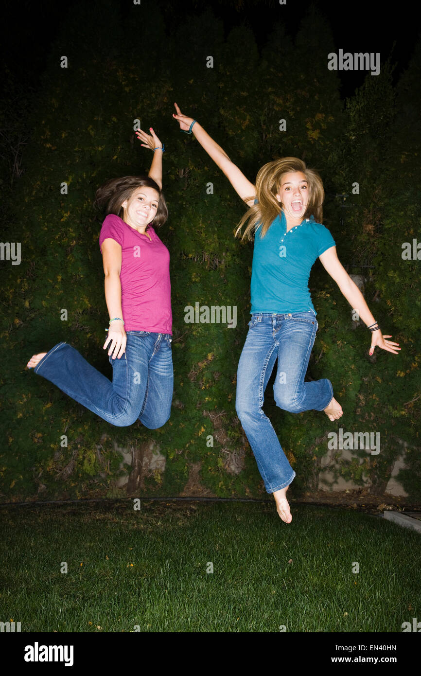 two girls jumping in the backyard at night Stock Photo - Alamy
