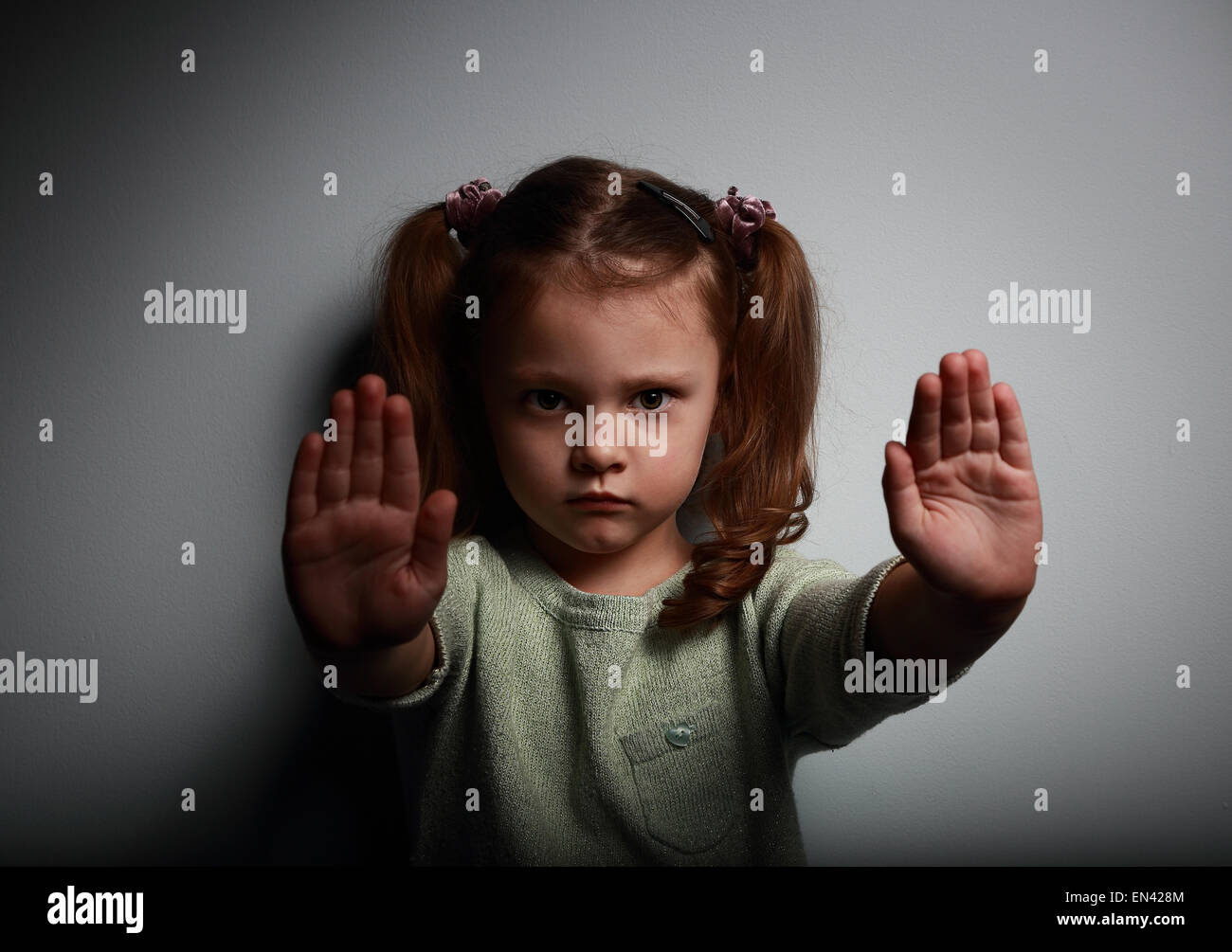 Kid girl showing two hands signaling to stop violence and pain on dark ...
