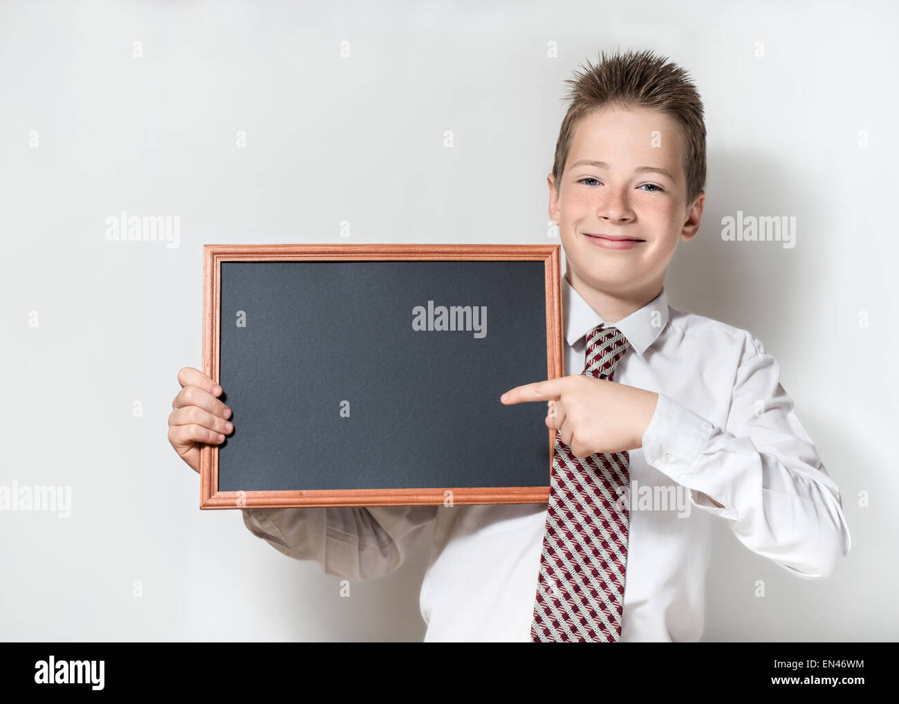 Smiling schoolboy pointing finger at empty chalkboard Stock Photo - Alamy