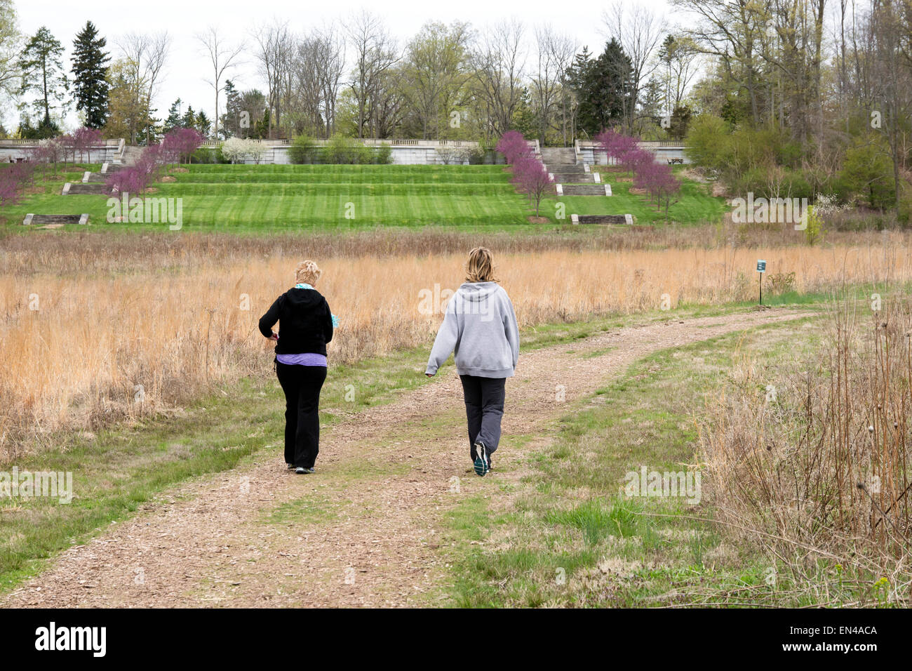 Two women walking on a path in the park in early spring Stock Photo - Alamy