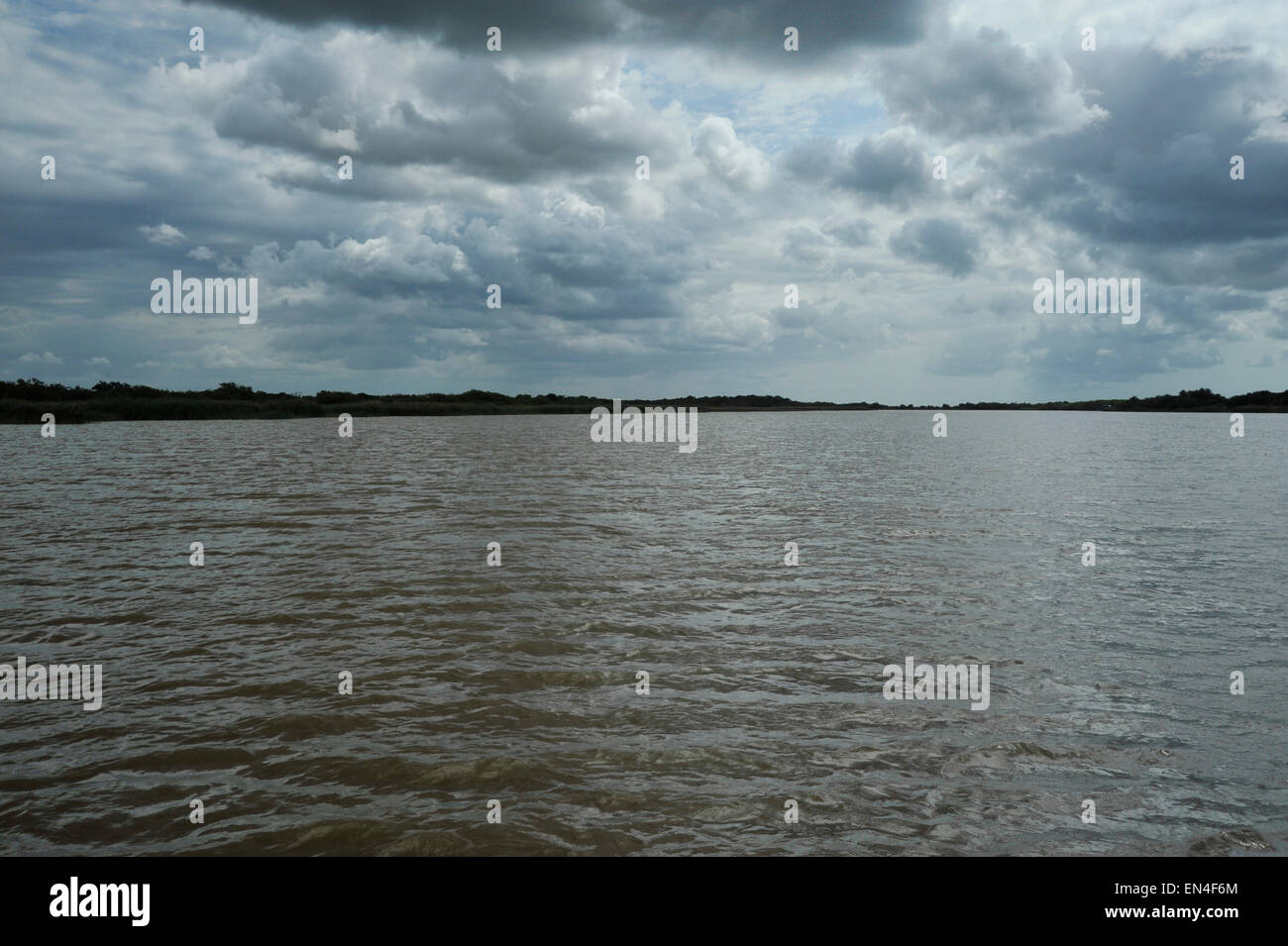 Dramatic threatening clouds forming over open brown water during a ...