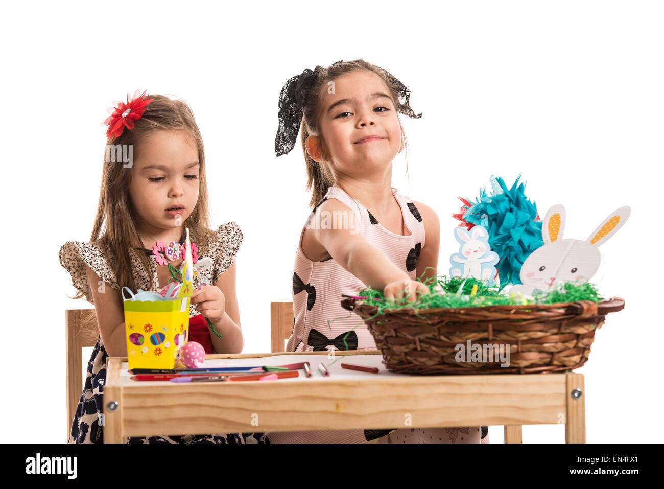 Two girls sitting on chairs at table and painting Easter eggs Stock ...