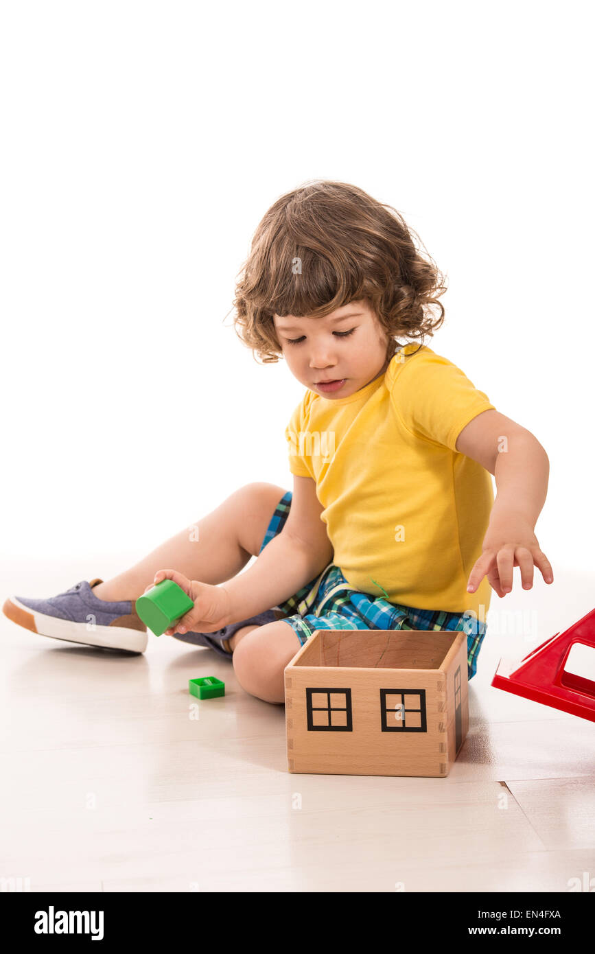Toddler boy playing with wood house toy adding cubes Stock Photo - Alamy