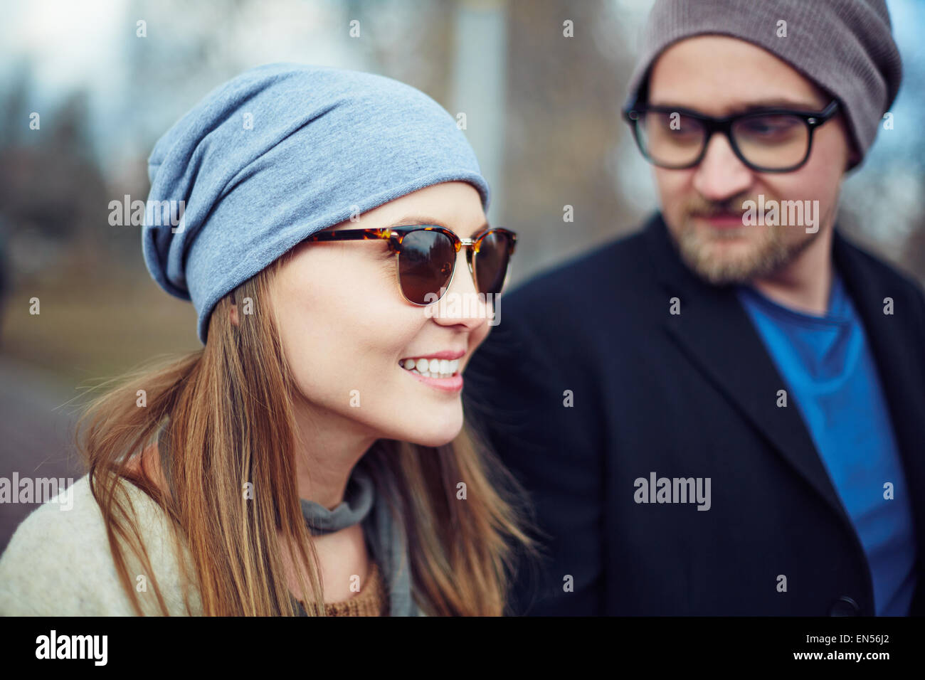 Happy young woman in cap and sunglasses on background of her boyfriend ...