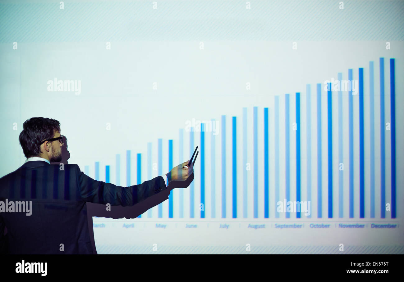 Rear view of businessman explaining chart on the wall Stock Photo - Alamy