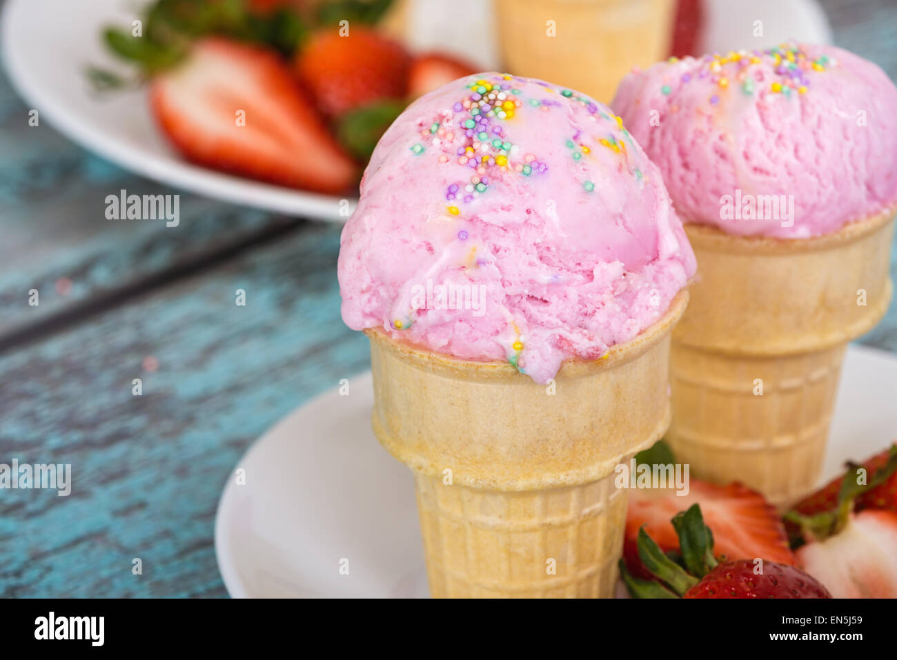 Strawberry ice cream with sprinkles in waffle cups against wooden ...