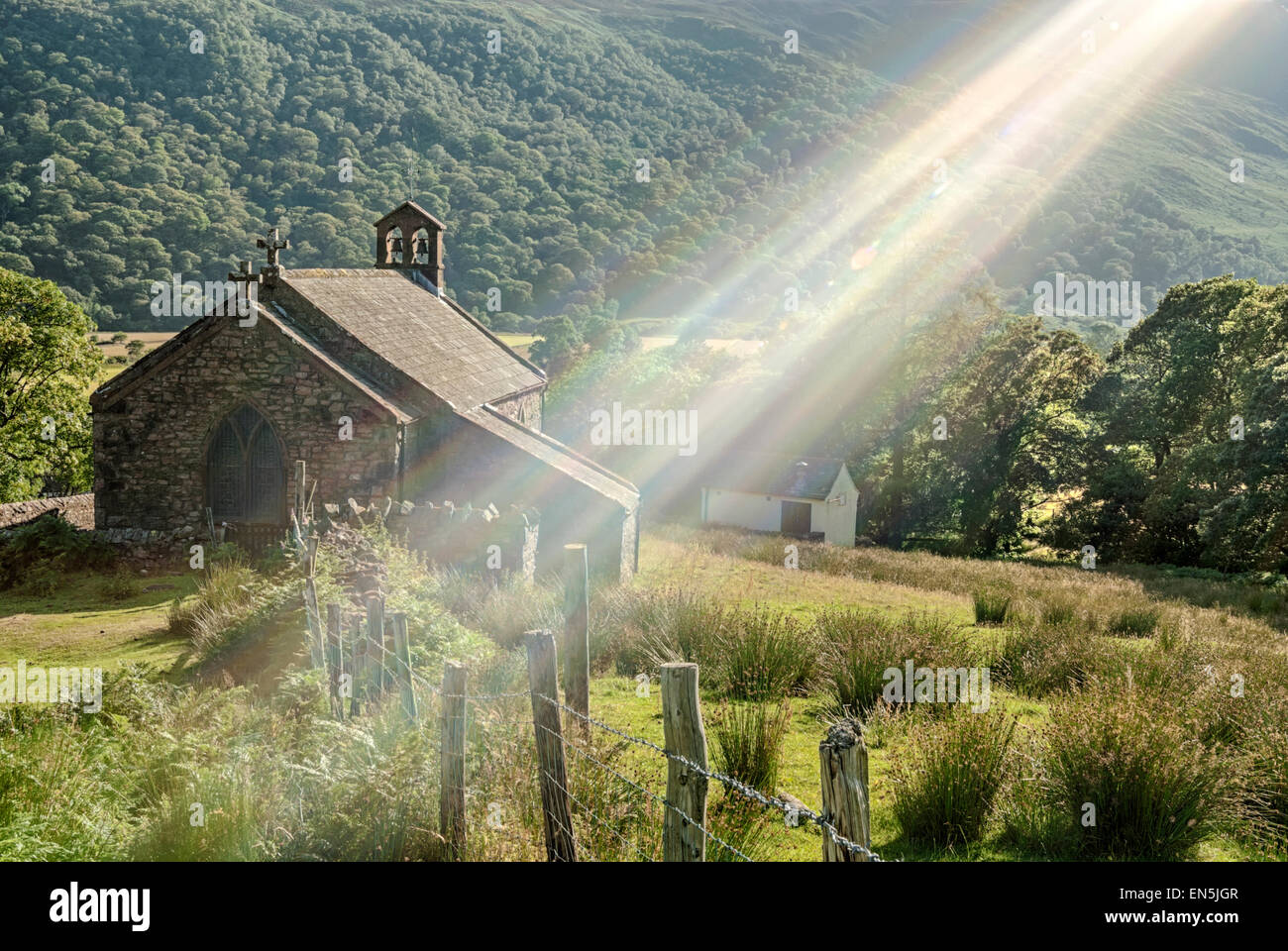 Village church of Buttermere backlit by a strong sunbeam, Lake District ...