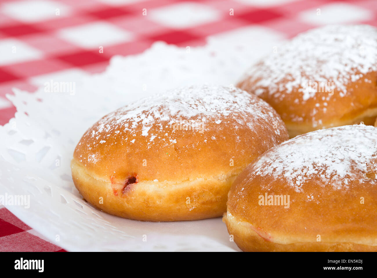 Fresh raspberry filled donuts topped with powdered sugar on a plate ...