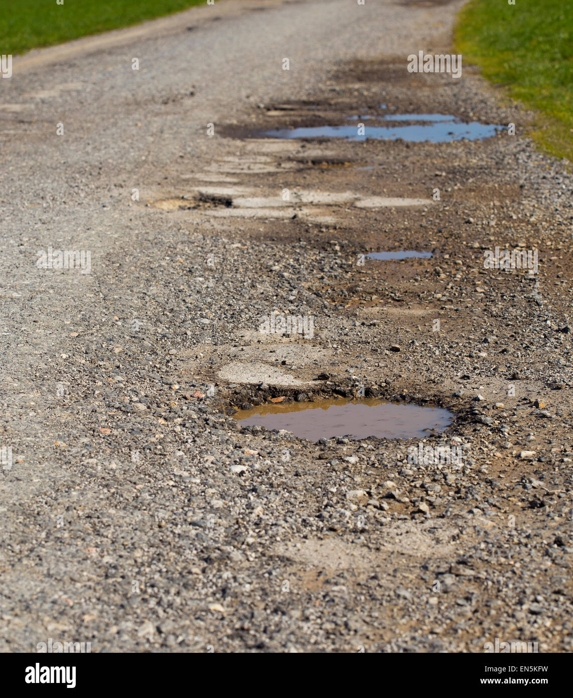 Puddle on old cracked asphalt road Stock Photo - Alamy