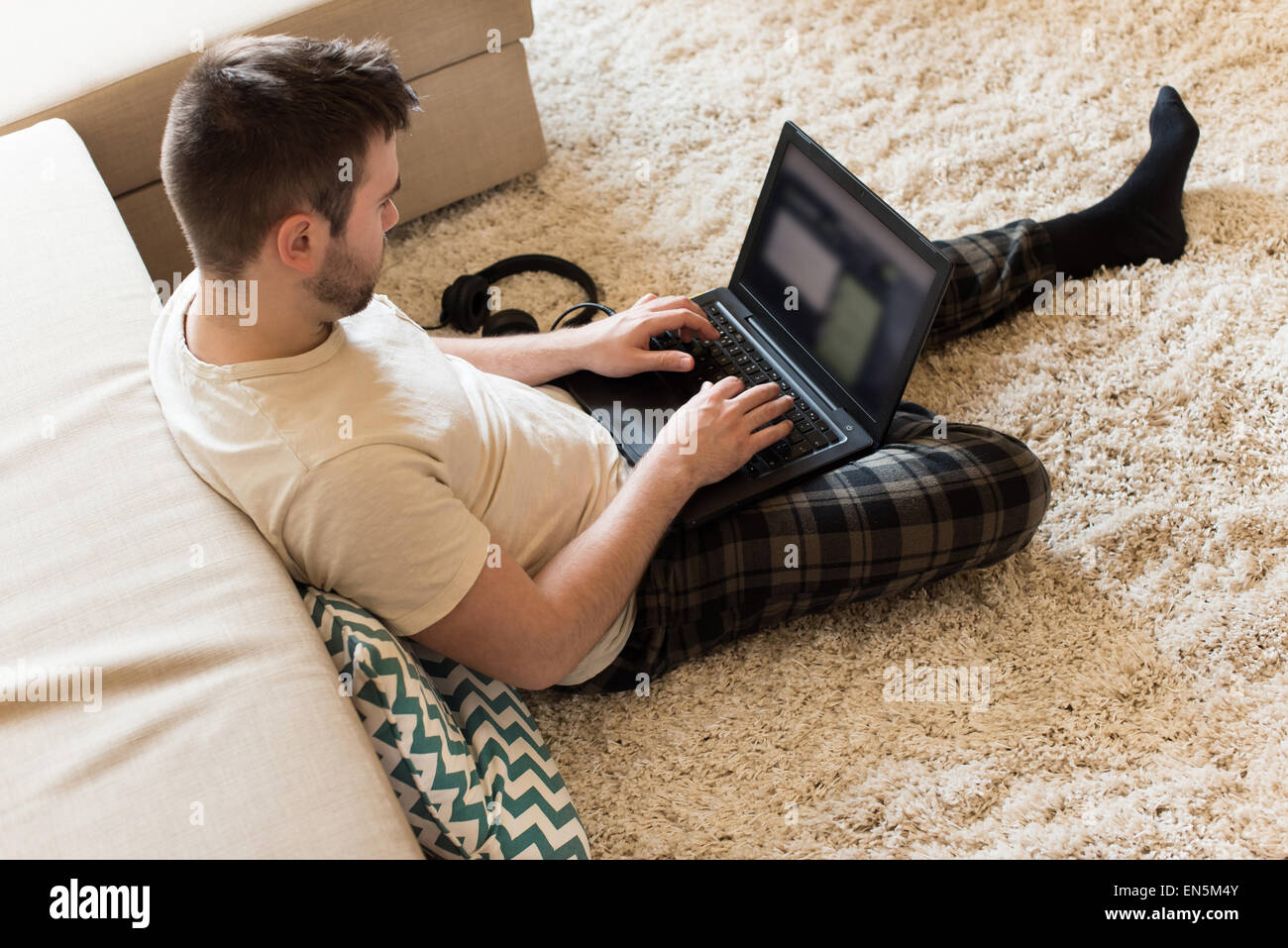 Man lying on the floor typing on laptop - Focus on laptop Stock Photo ...