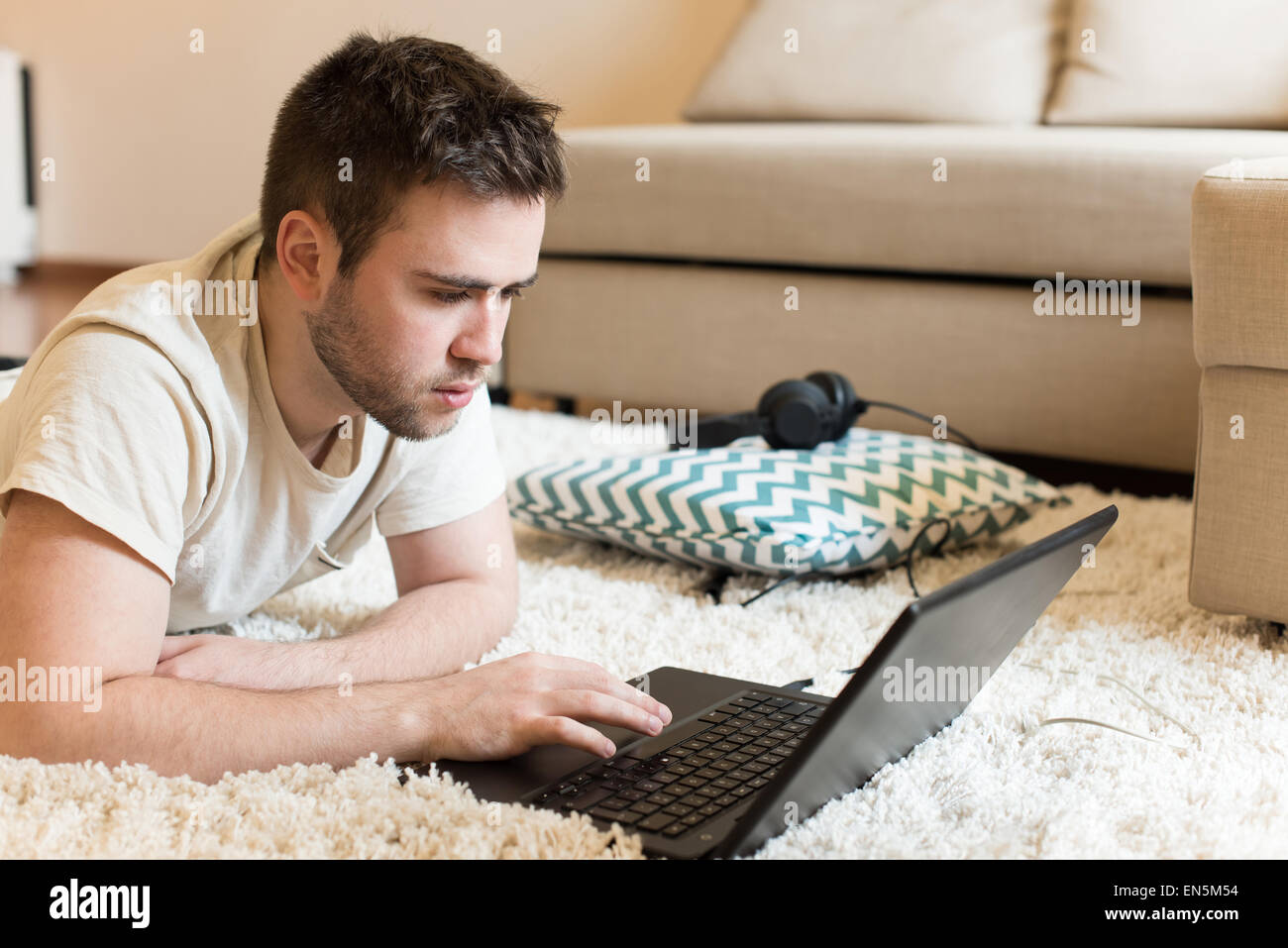Man lying on the floor typing on laptop Stock Photo - Alamy