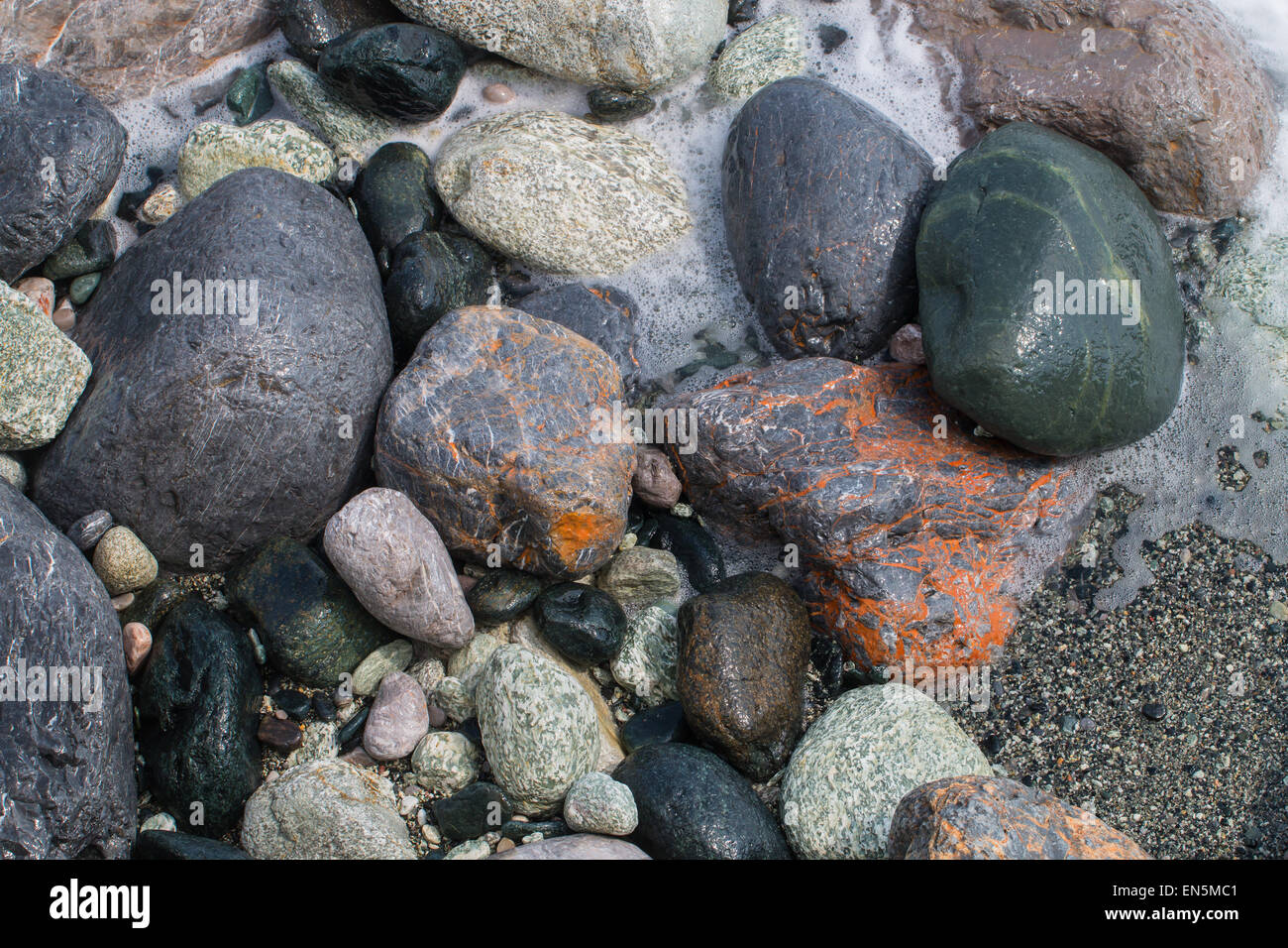 colorful striped stones wet and rounded by waves. detail of liguria ...