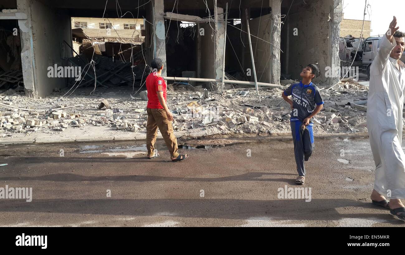 Fallujah, Iraq. 28th Apr, 2015. People stand by a damaged building ...