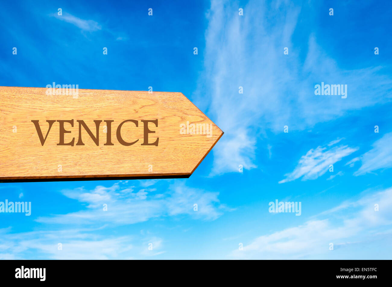 Wooden arrow sign pointing destination VENICE against clear blue sky ...