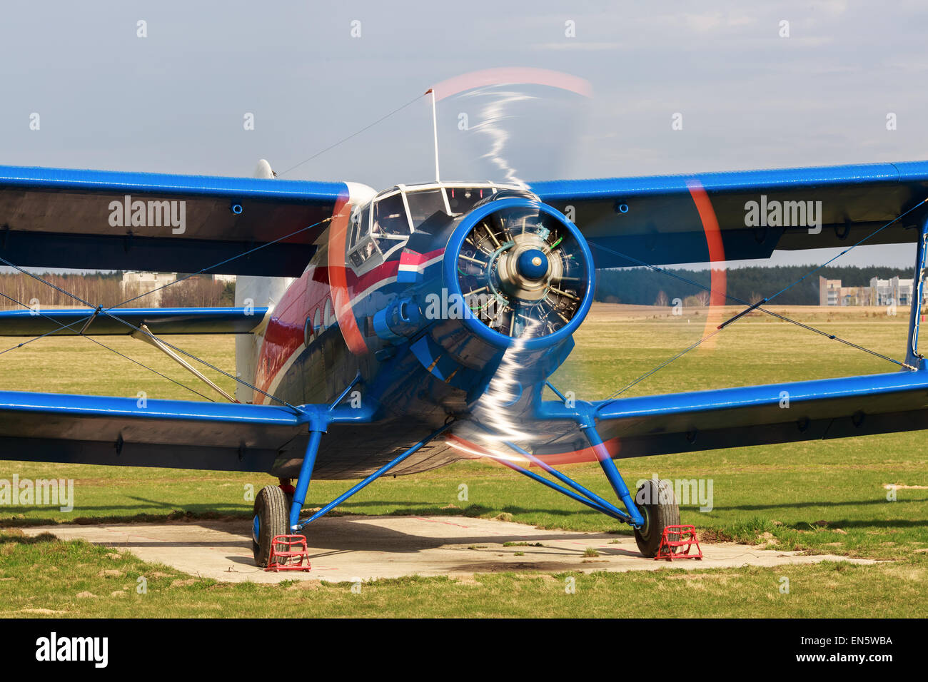 Old bright blue airplane with a rotating propeller close-up. Front view ...