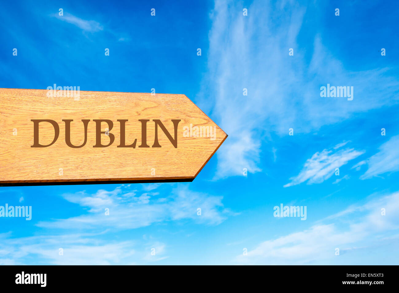Wooden arrow sign pointing destination DUBLIN against clear blue sky ...