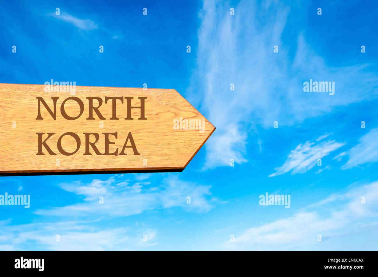 Wooden arrow sign pointing destination NORTH KOREA against clear blue ...