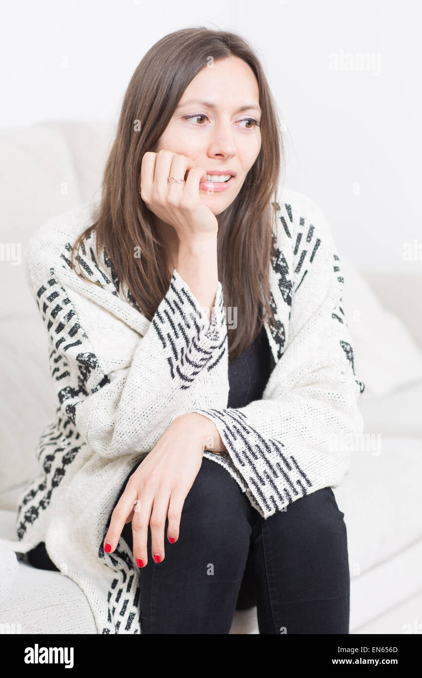 brunette woman thinking while sitting on coach Stock Photo - Alamy