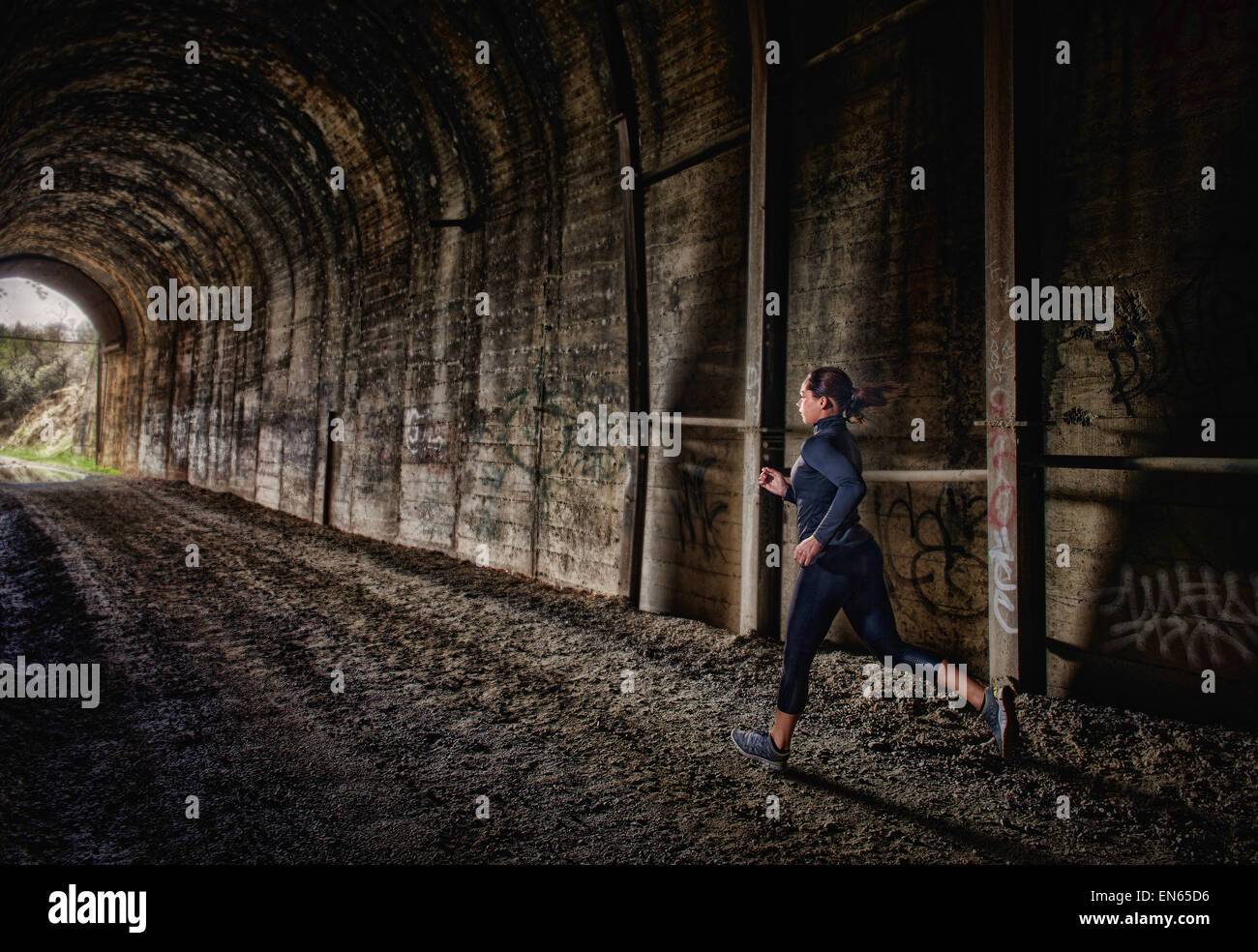 A young woman running through a tunnel as part of her morning fitness ...