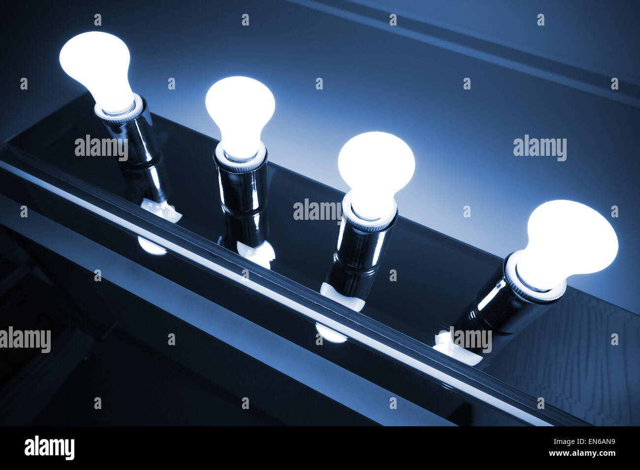 Four shining electrical lamps in a row, modern blue toned illumination ...