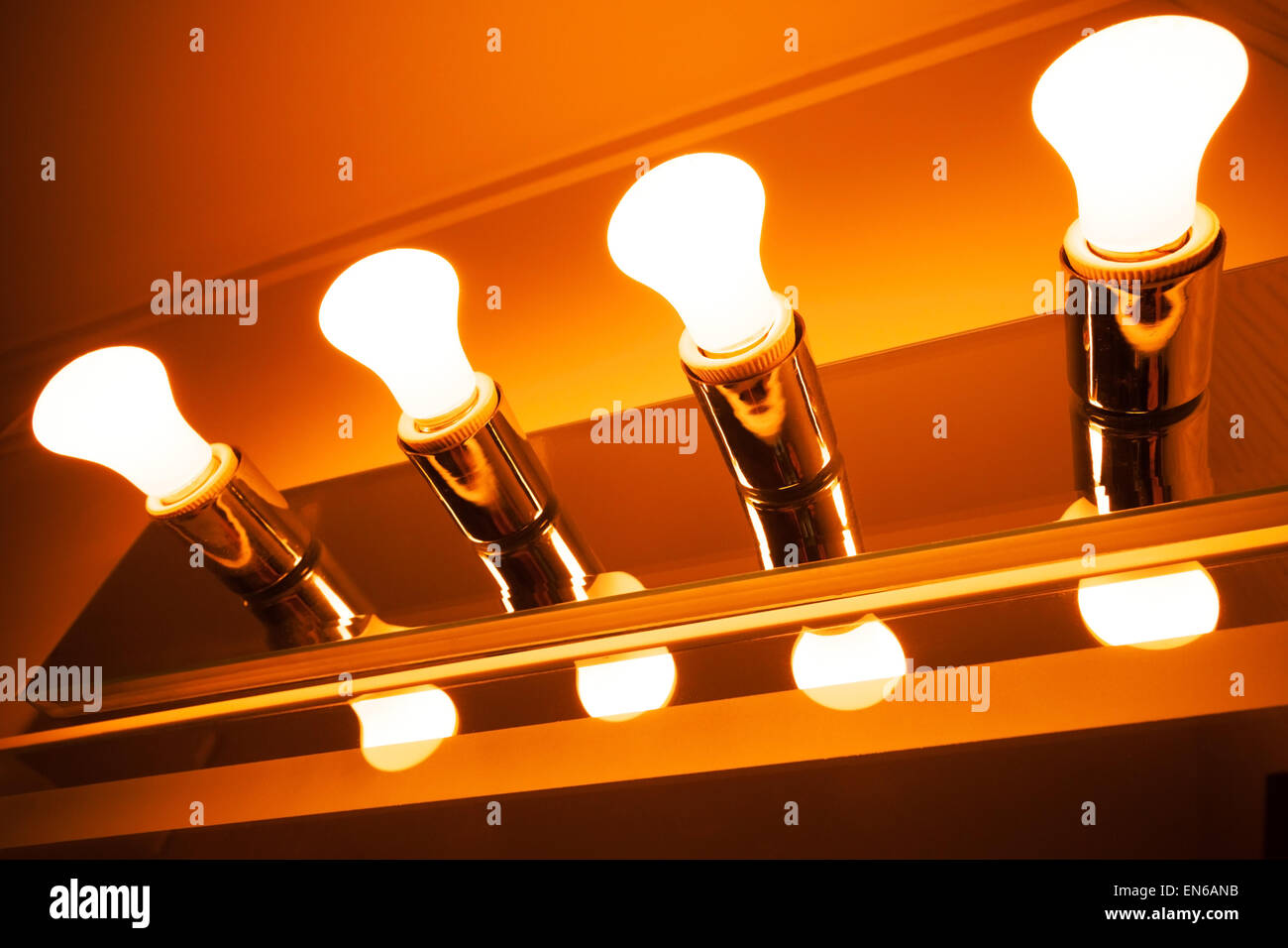 Four shining electrical lamps in a row, modern orange toned ...