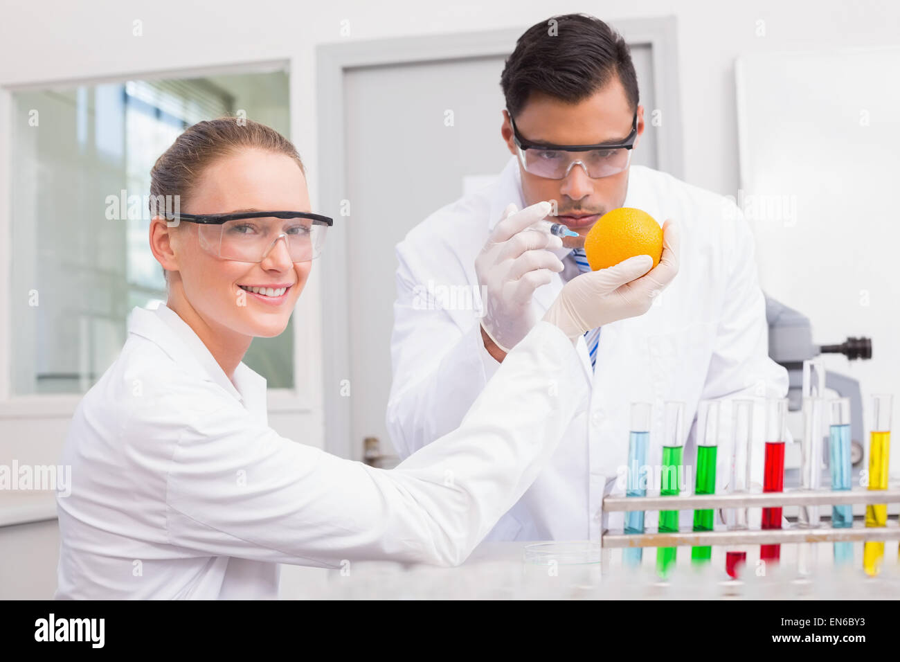 Scientists injecting orange Stock Photo - Alamy