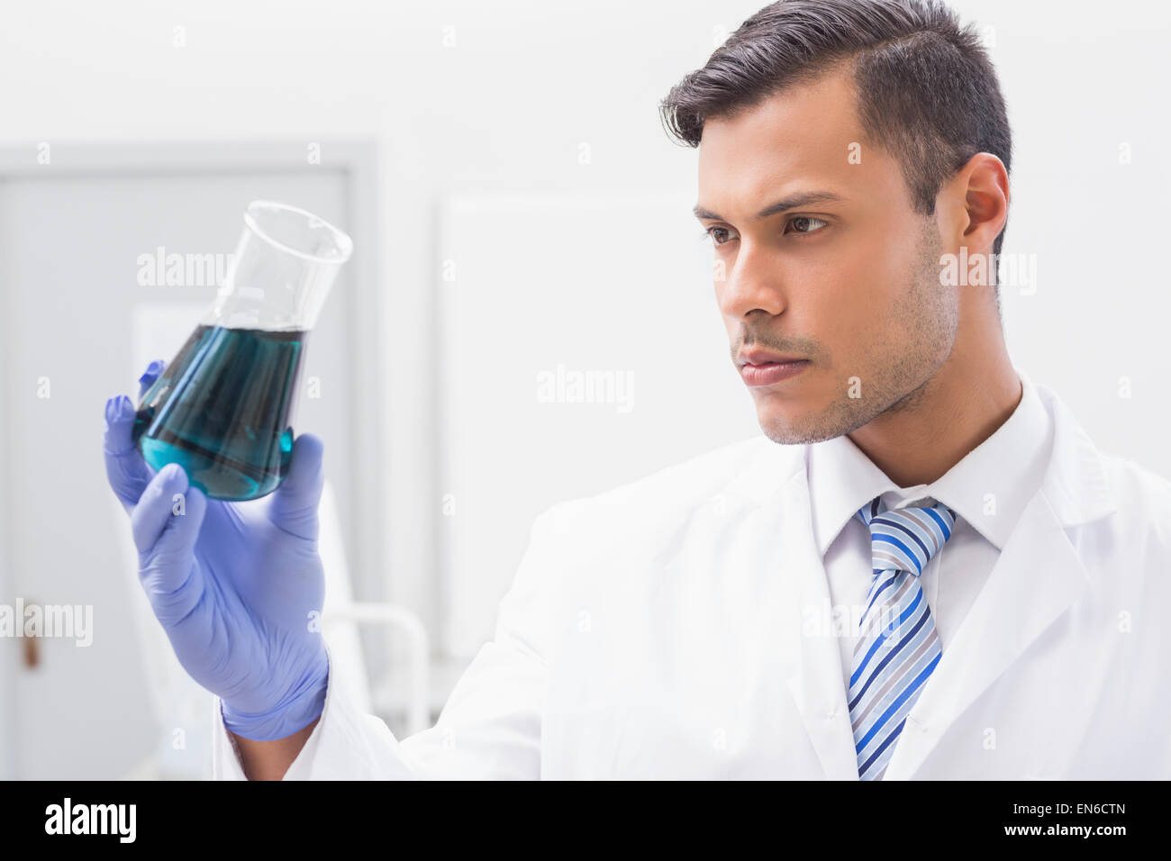Concentrated scientist looking at beaker Stock Photo - Alamy