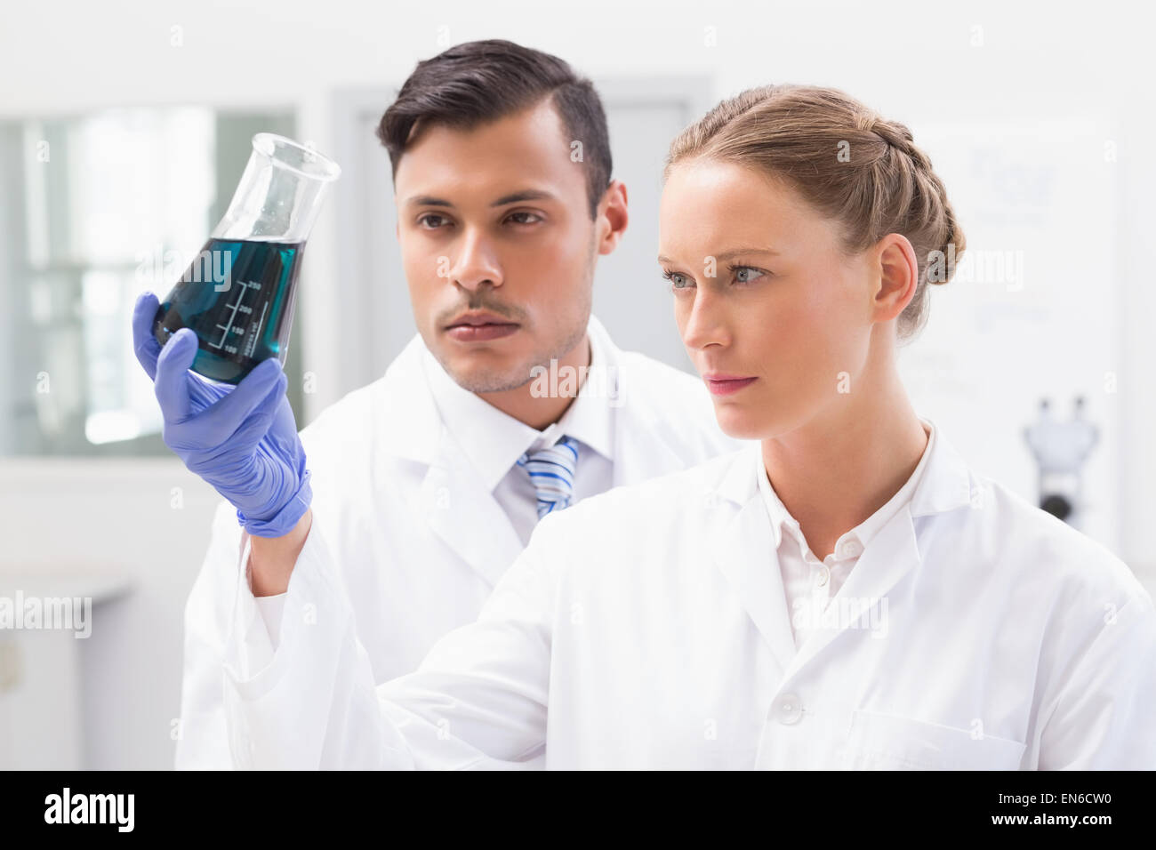 Concentrated scientists holding beaker with fluid Stock Photo - Alamy