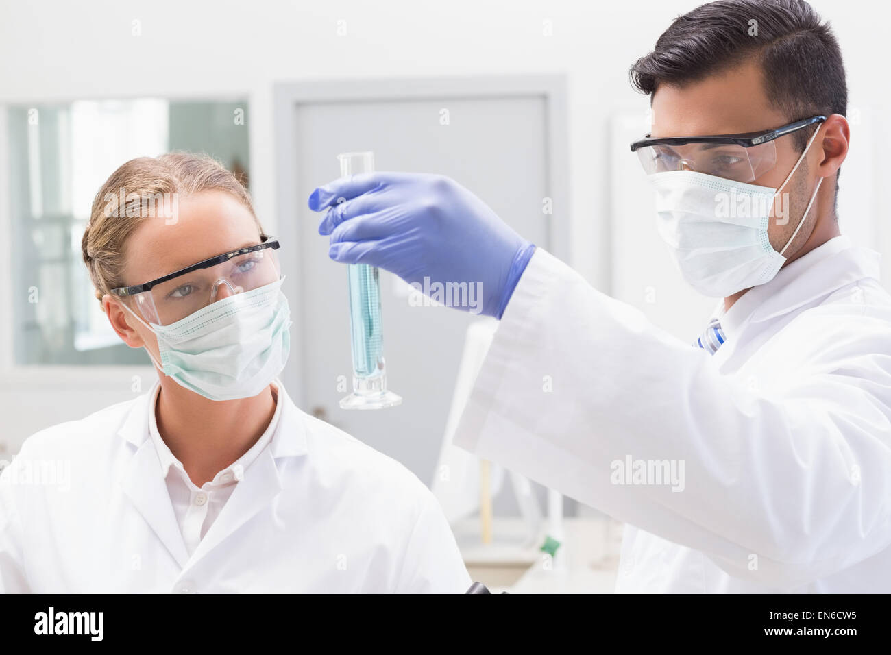 Concentrated scientists looking at beaker Stock Photo - Alamy