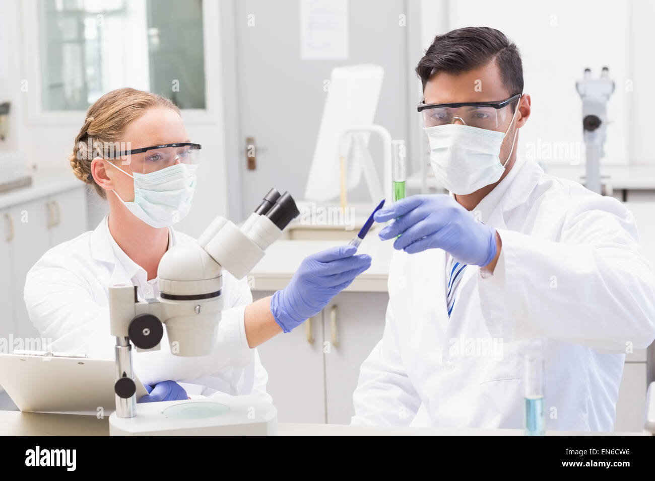 Concentrated scientists looking at beaker Stock Photo - Alamy