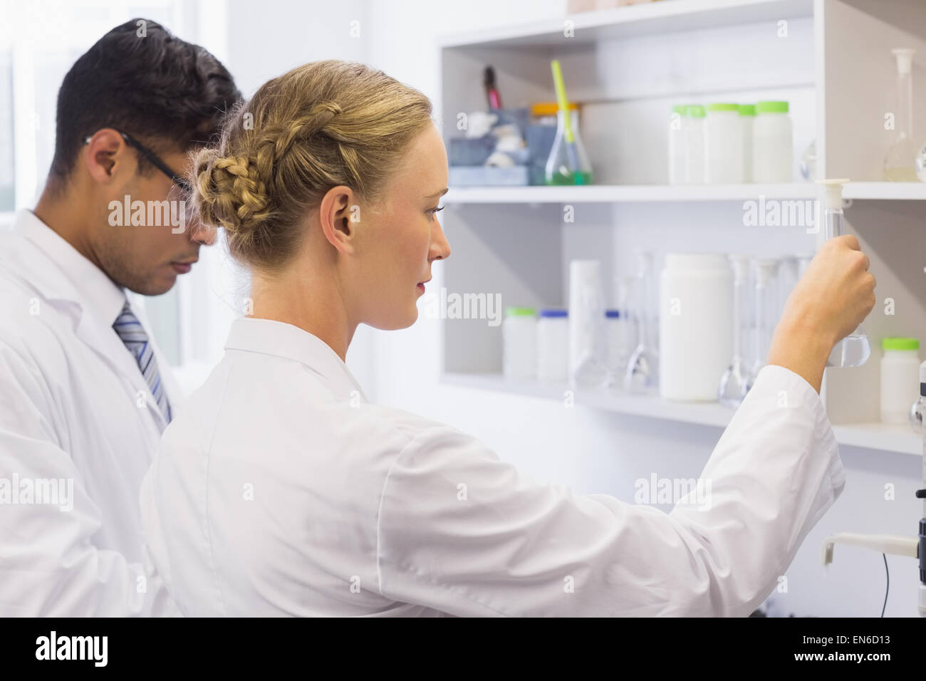 Concentrated scientists looking at beaker Stock Photo - Alamy