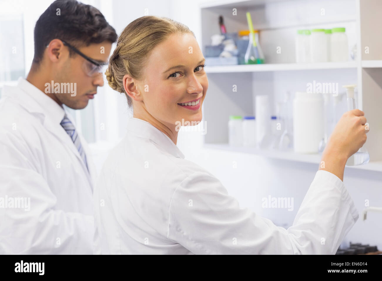 Smiling scientist looking at camera and holding a beaker Stock Photo ...