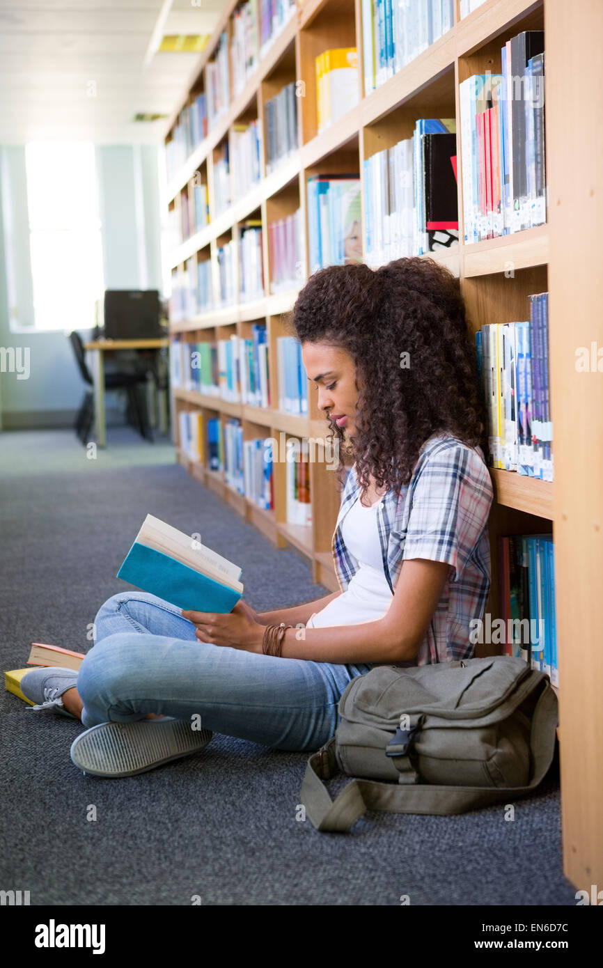 Student sitting on floor in library reading Stock Photo - Alamy