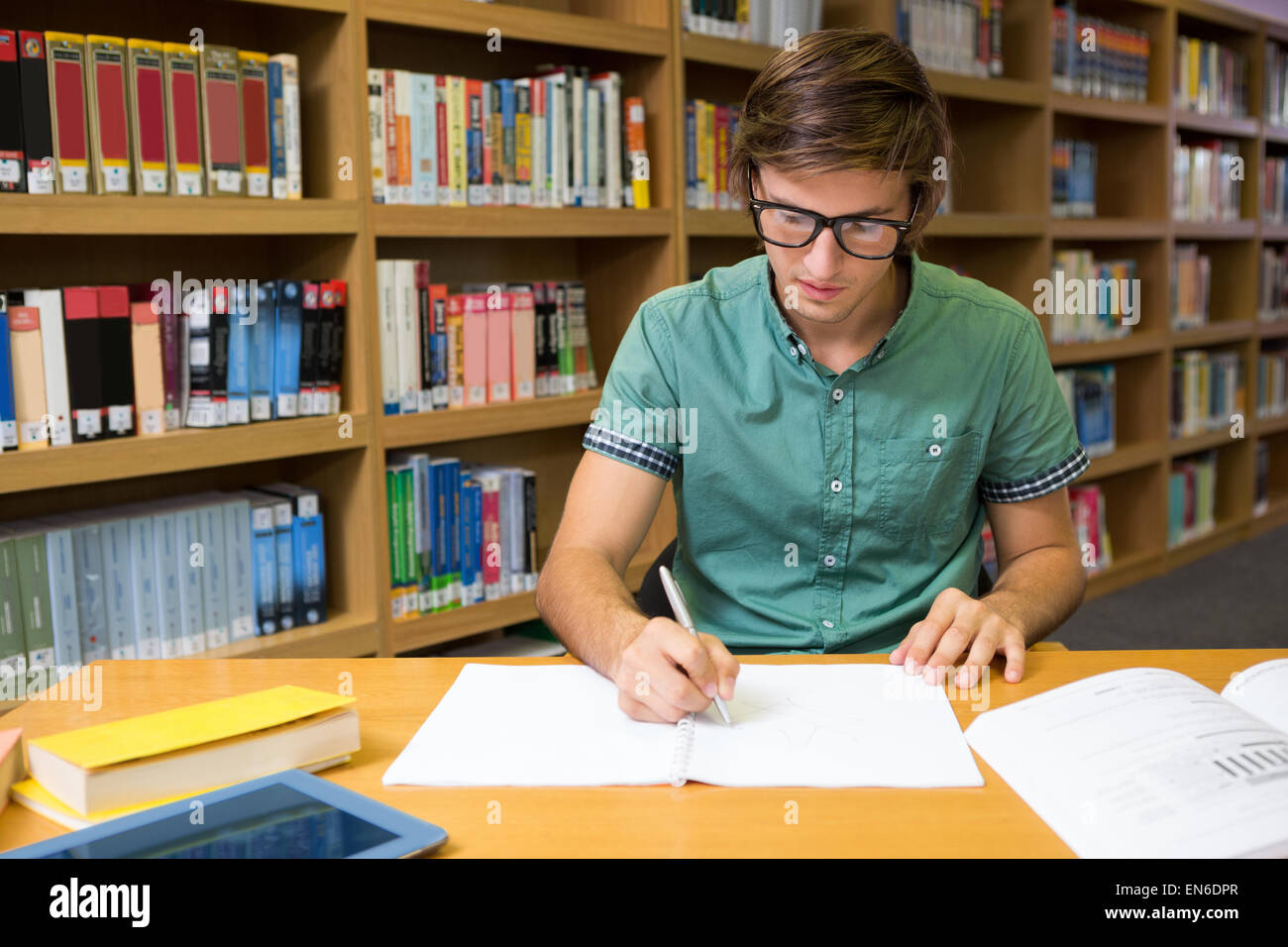 Student sitting in library writing Stock Photo - Alamy