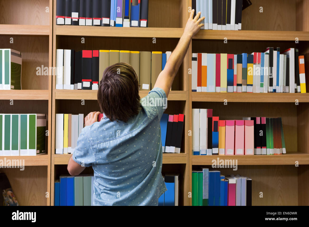 Student picking a book from shelf in library Stock Photo - Alamy