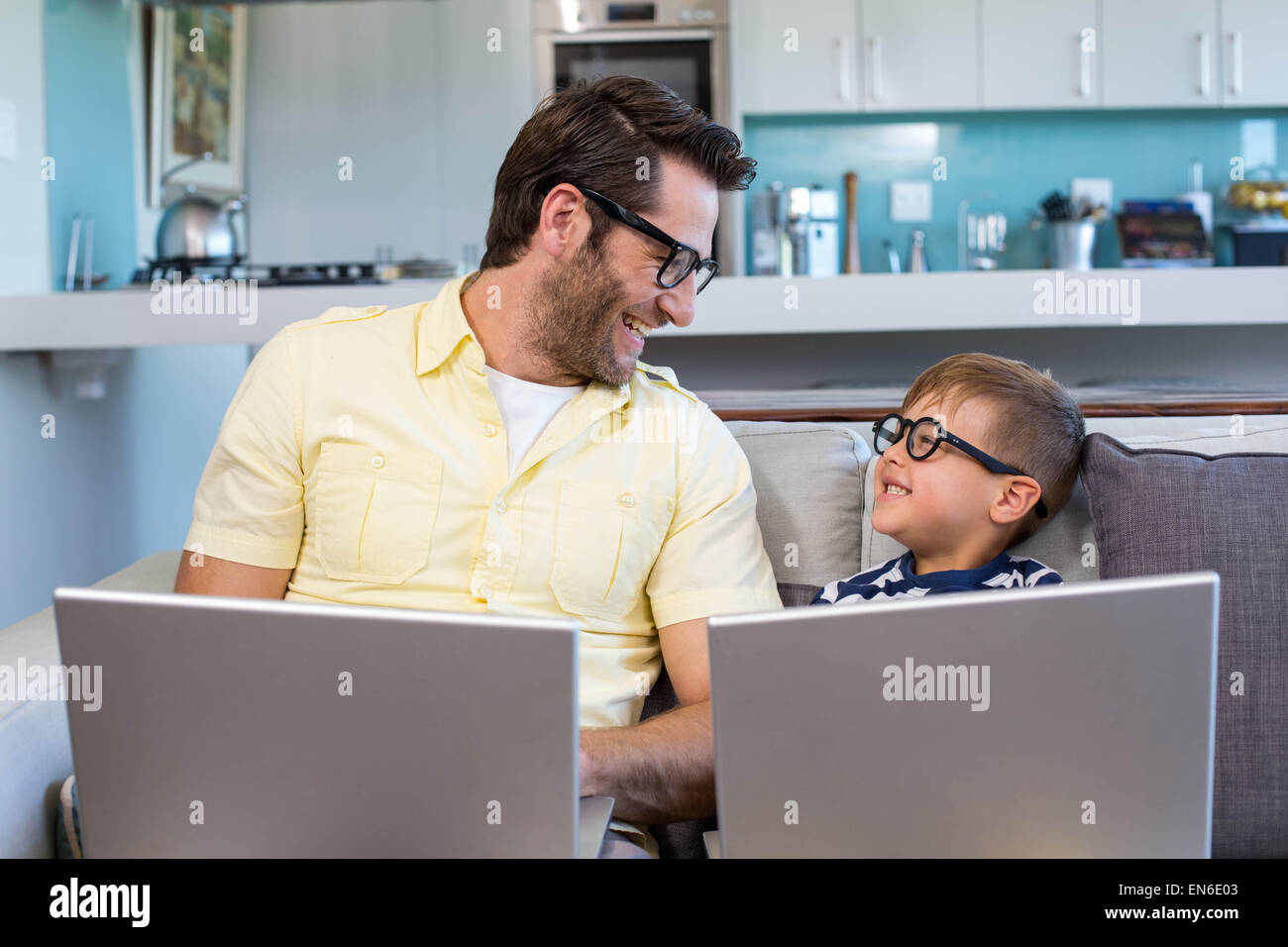 Father and son using laptops on the couch Stock Photo - Alamy