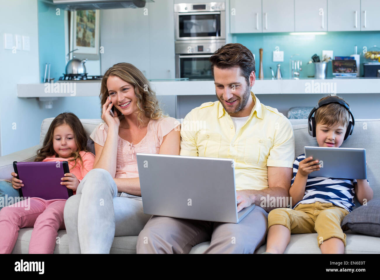 Happy family on the couch together using devices Stock Photo - Alamy