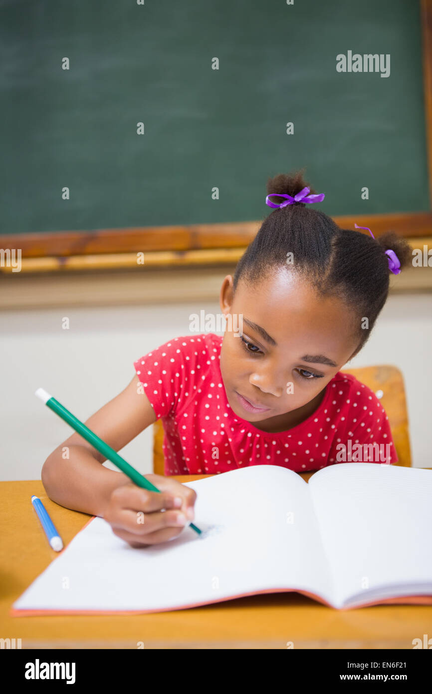 Cute pupil writing at desk in classroom Stock Photo - Alamy