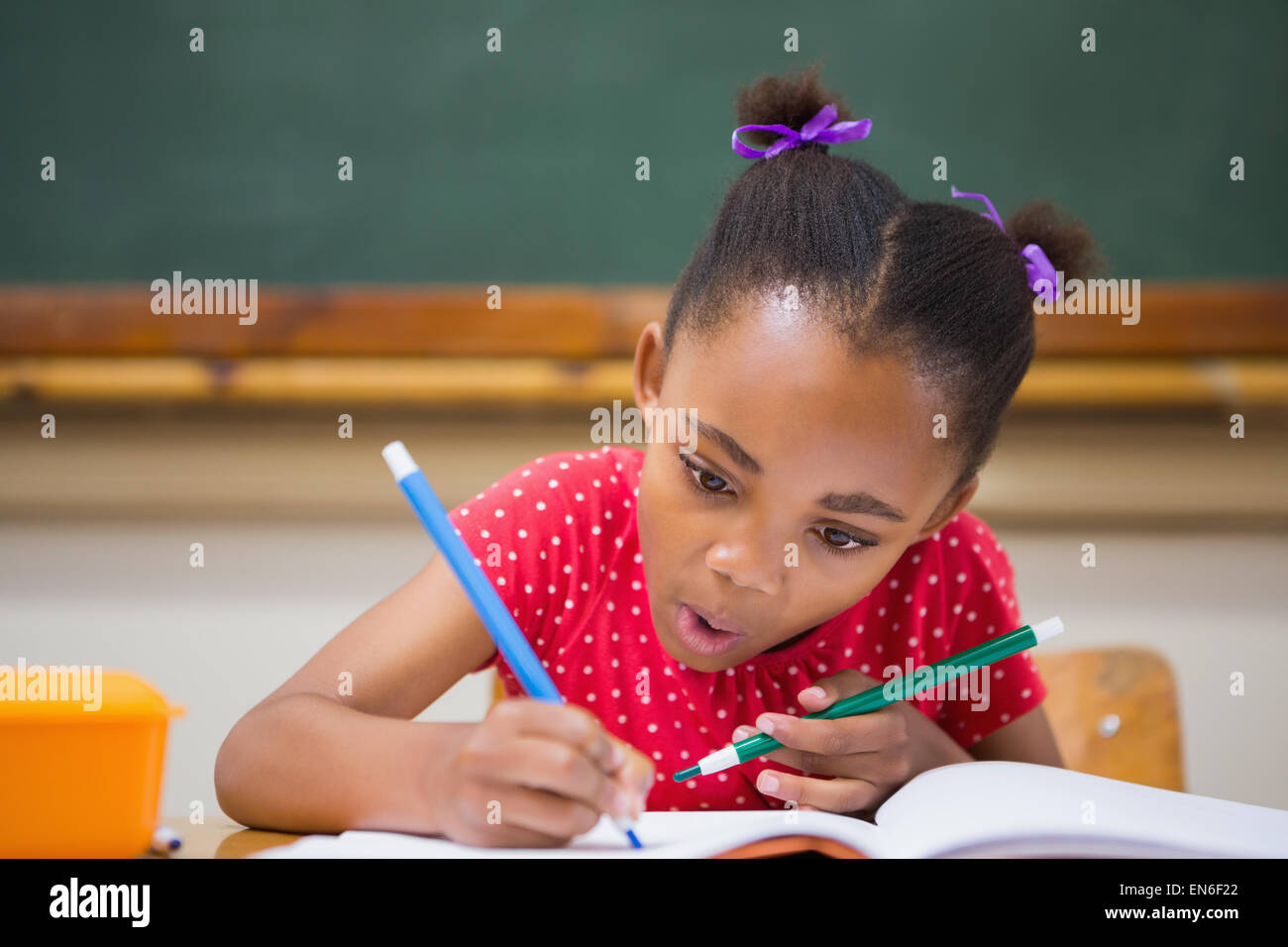 Cute pupil writing at desk in classroom Stock Photo - Alamy