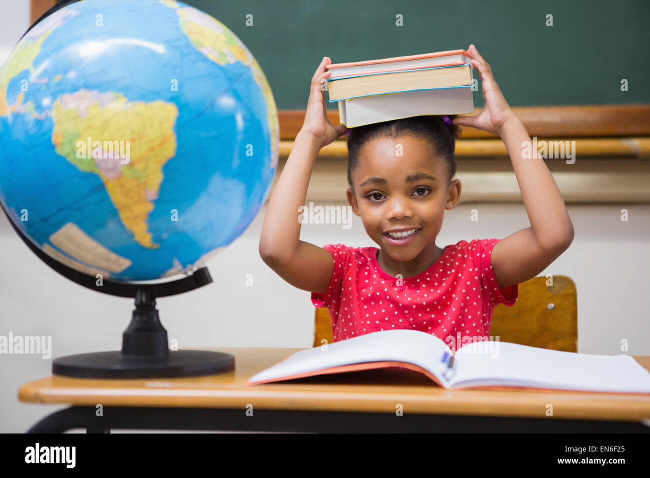 Cute pupil holding books on her head Stock Photo - Alamy