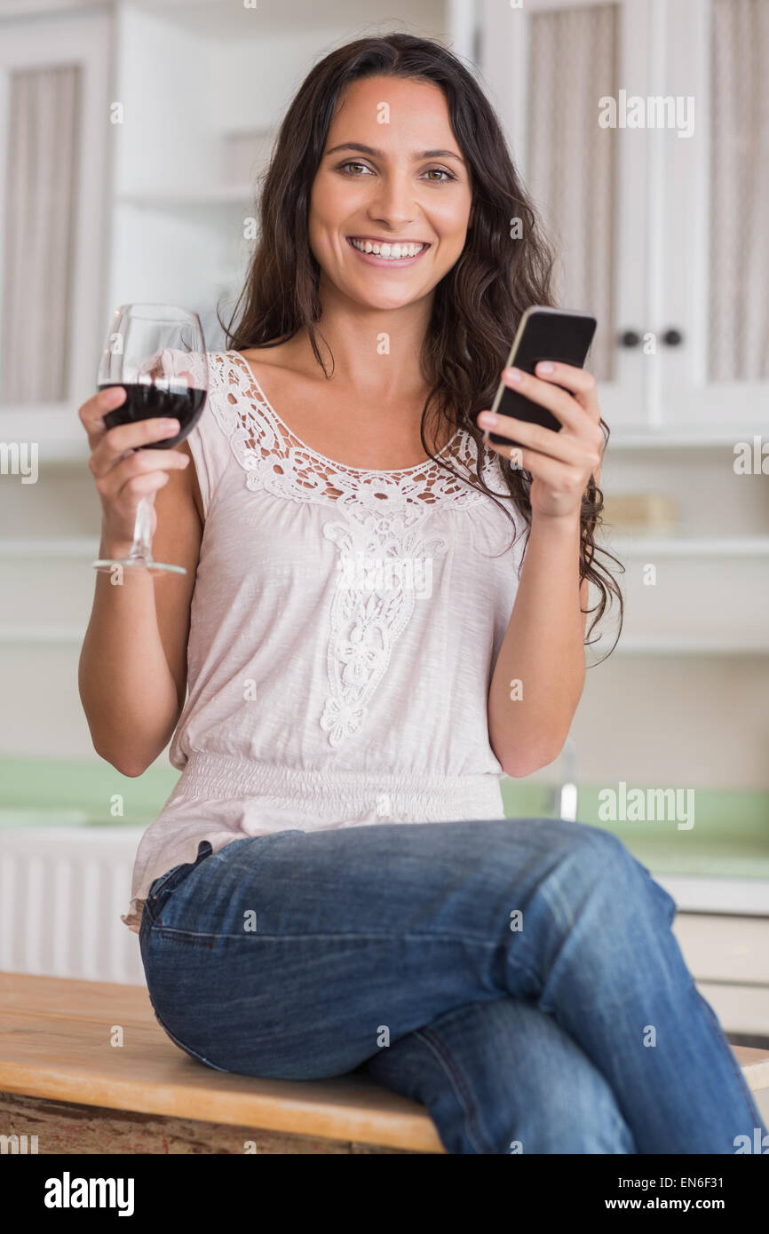 Pretty brunette using smartphone and having glass of wine Stock Photo ...