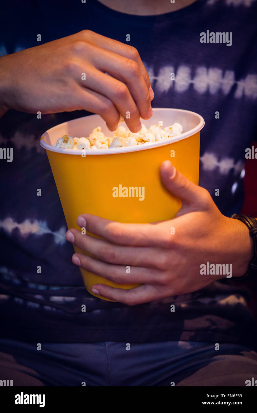 Young man watching a film and eating pop corn Stock Photo - Alamy