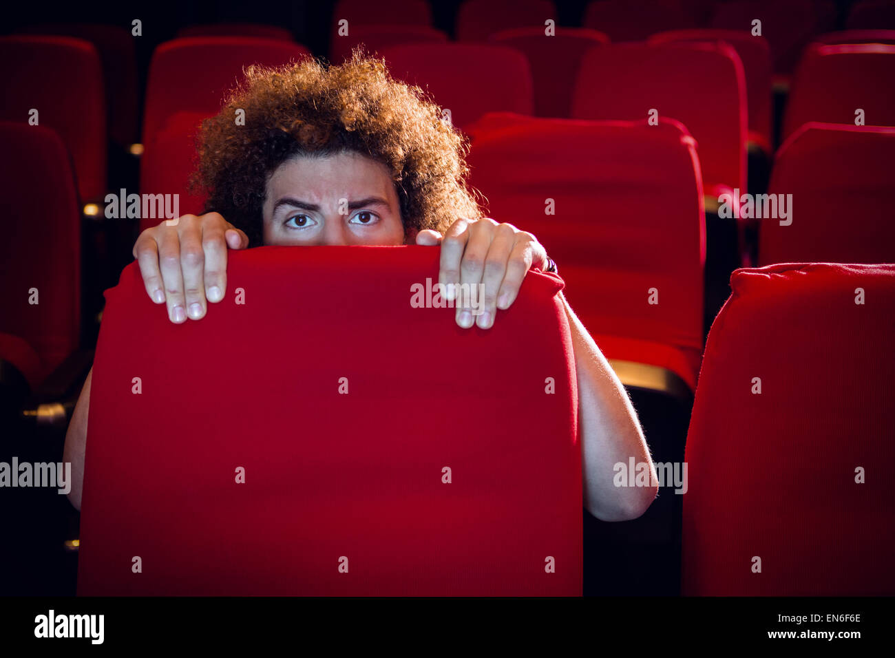 Young man watching a scary film Stock Photo - Alamy