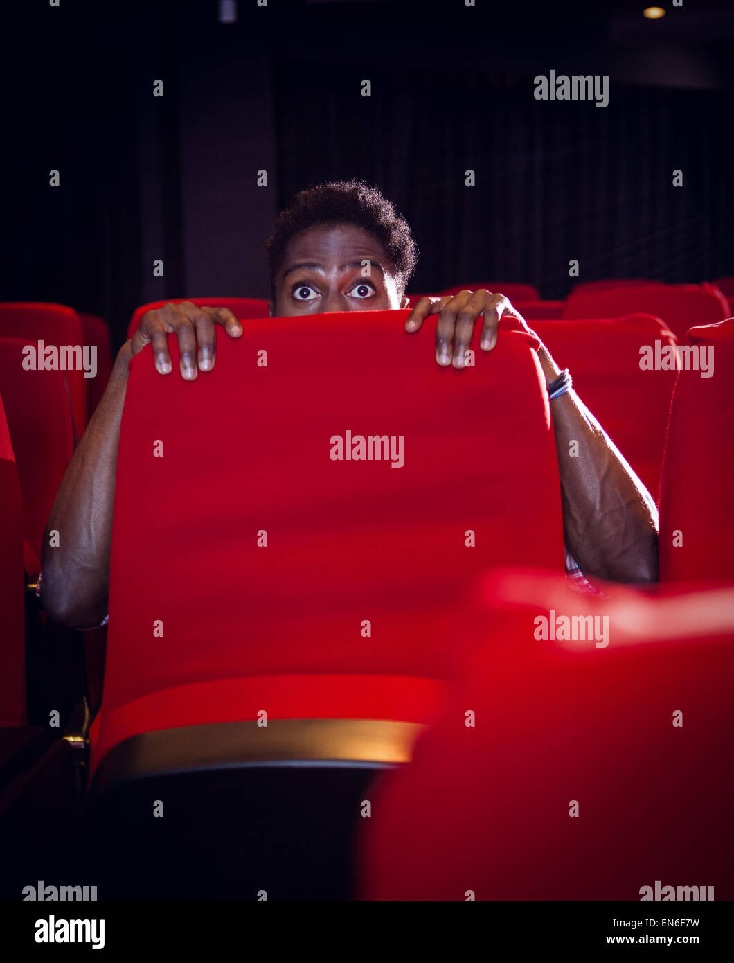 Young man watching a scary film Stock Photo - Alamy