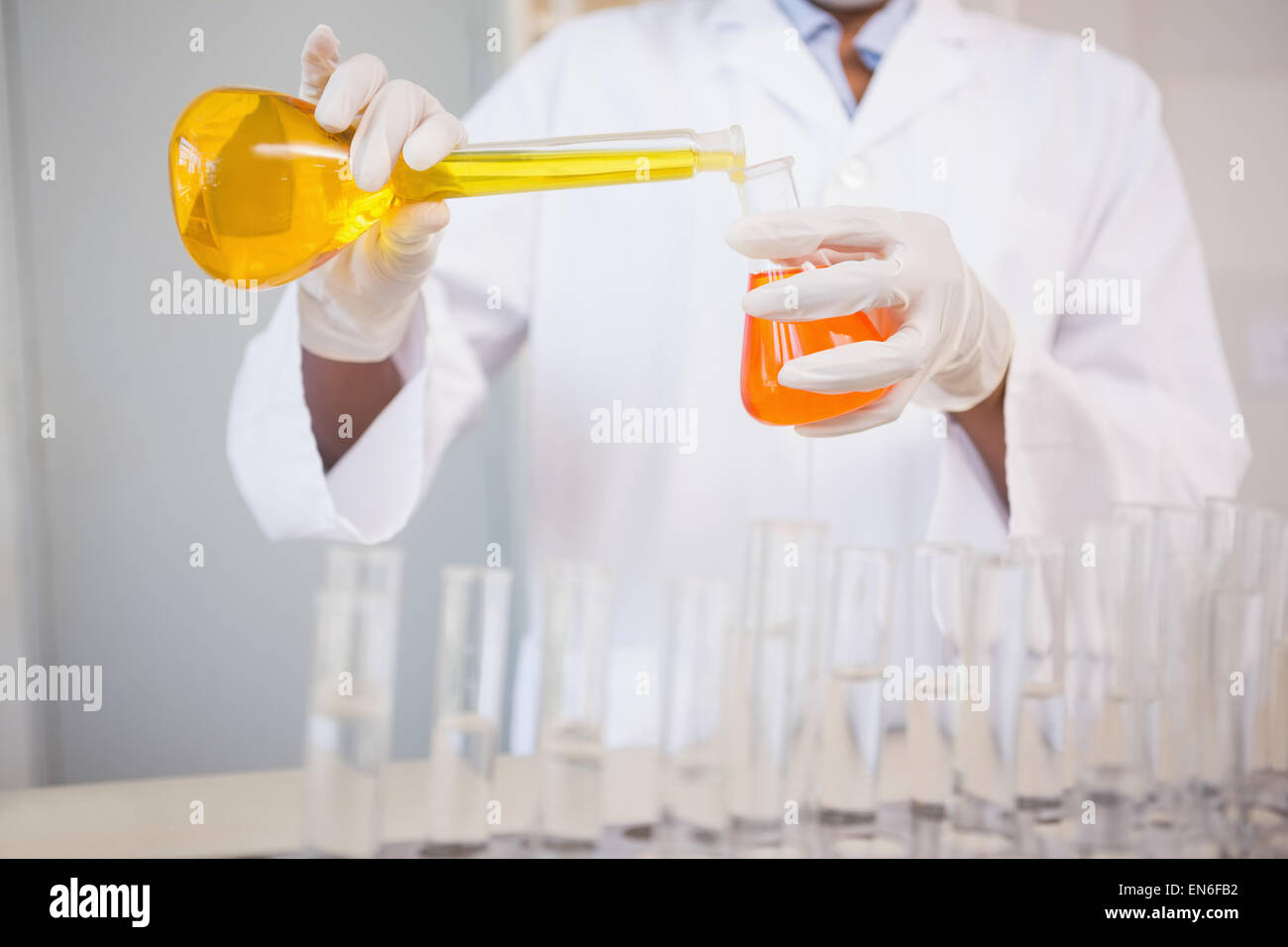 Concentrated scientist pouring orange fluid Stock Photo - Alamy